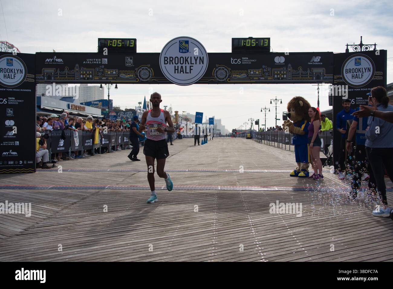 A male runner crosses the finish line of the Brooklyn Half marathon ...