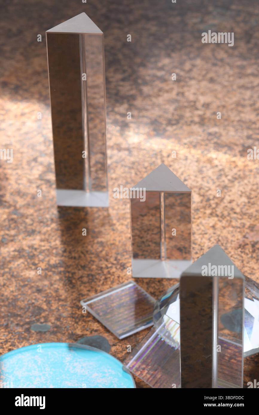 Three triangular glass objects are on a brown surface Stock Photo - Alamy