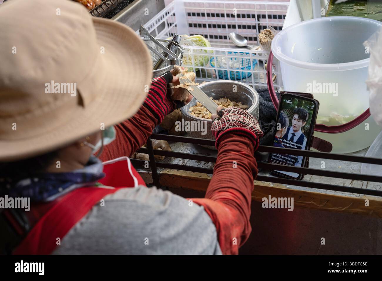 Bangkok, Thailand. March 25th 2025 A street vendor chops ginger while ...