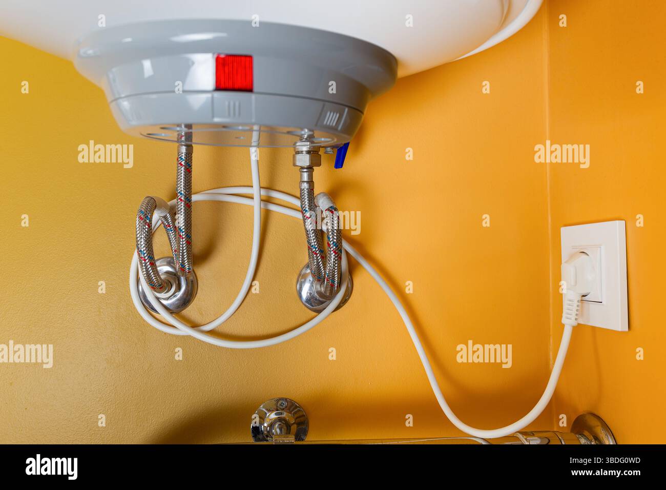 Electric water heater unit installed with braided hoses and white cord ...