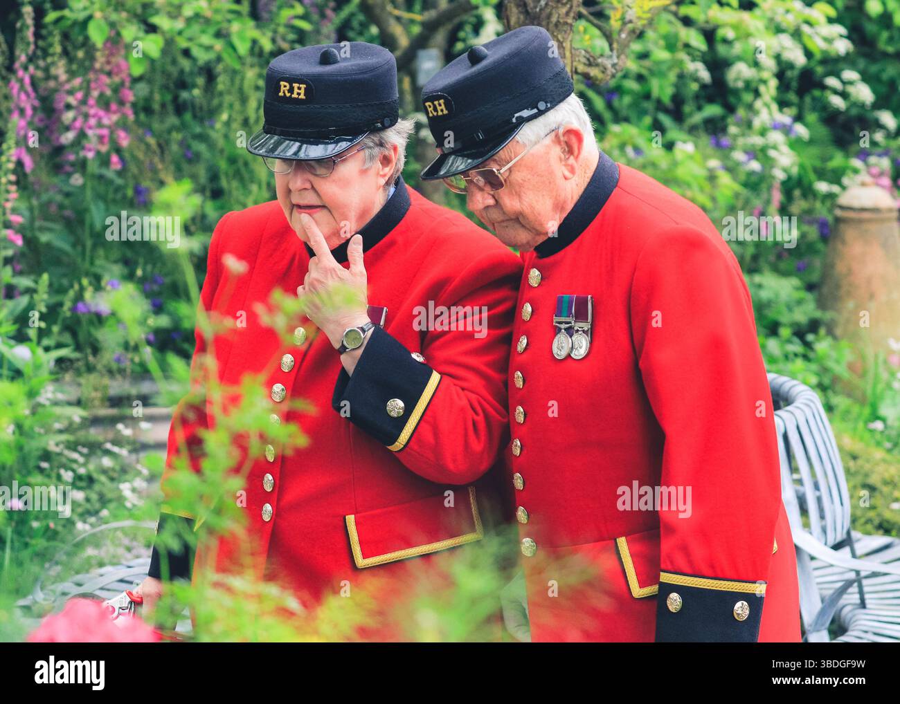 Two Chelsea Pensioners in their red uniforms look at the flowers at ...