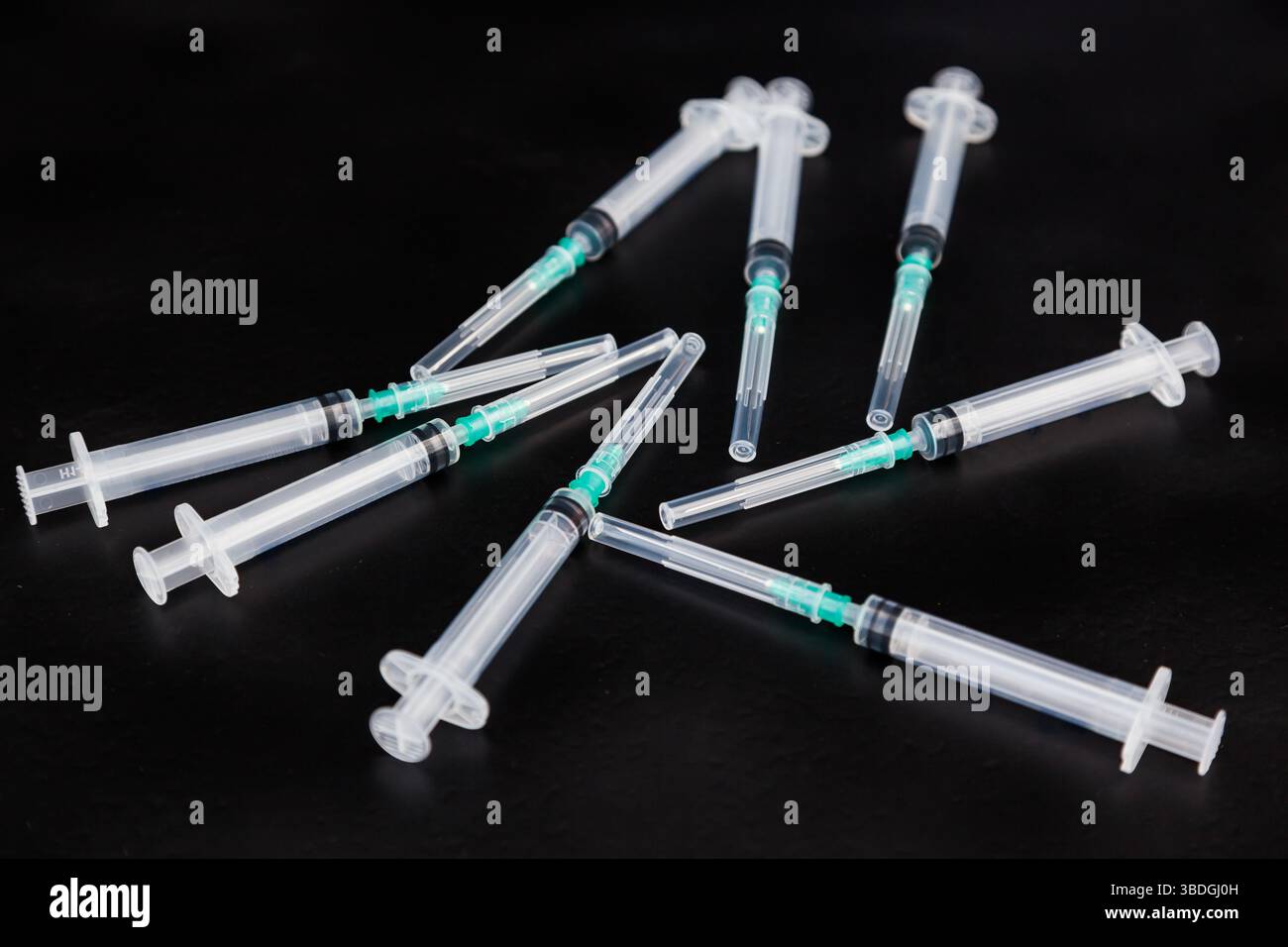 Syringes with inserted needles scattered on a black background Stock ...