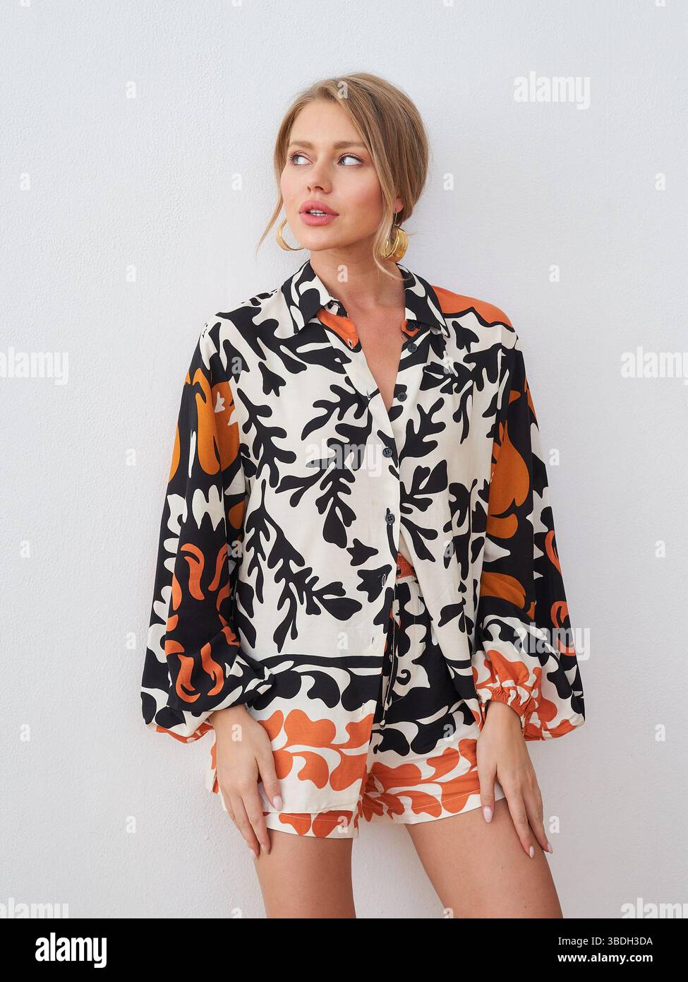 Beautiful blonde woman poses stylishly in a vibrant fashion outfit in a ...