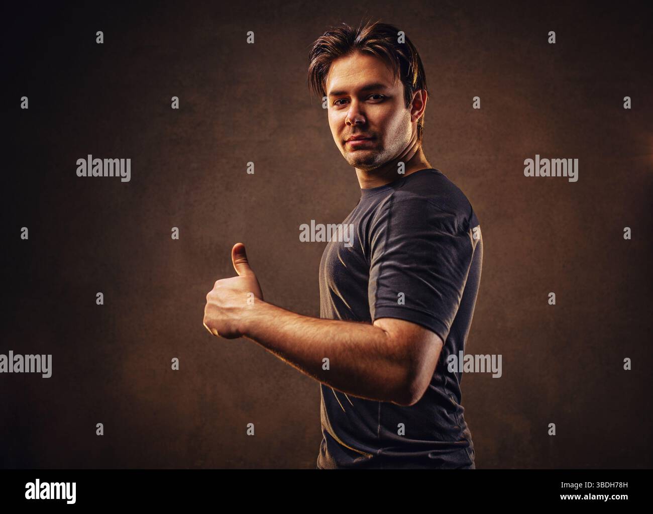 Young strong man showing thumbs up on wall background Stock Photo - Alamy
