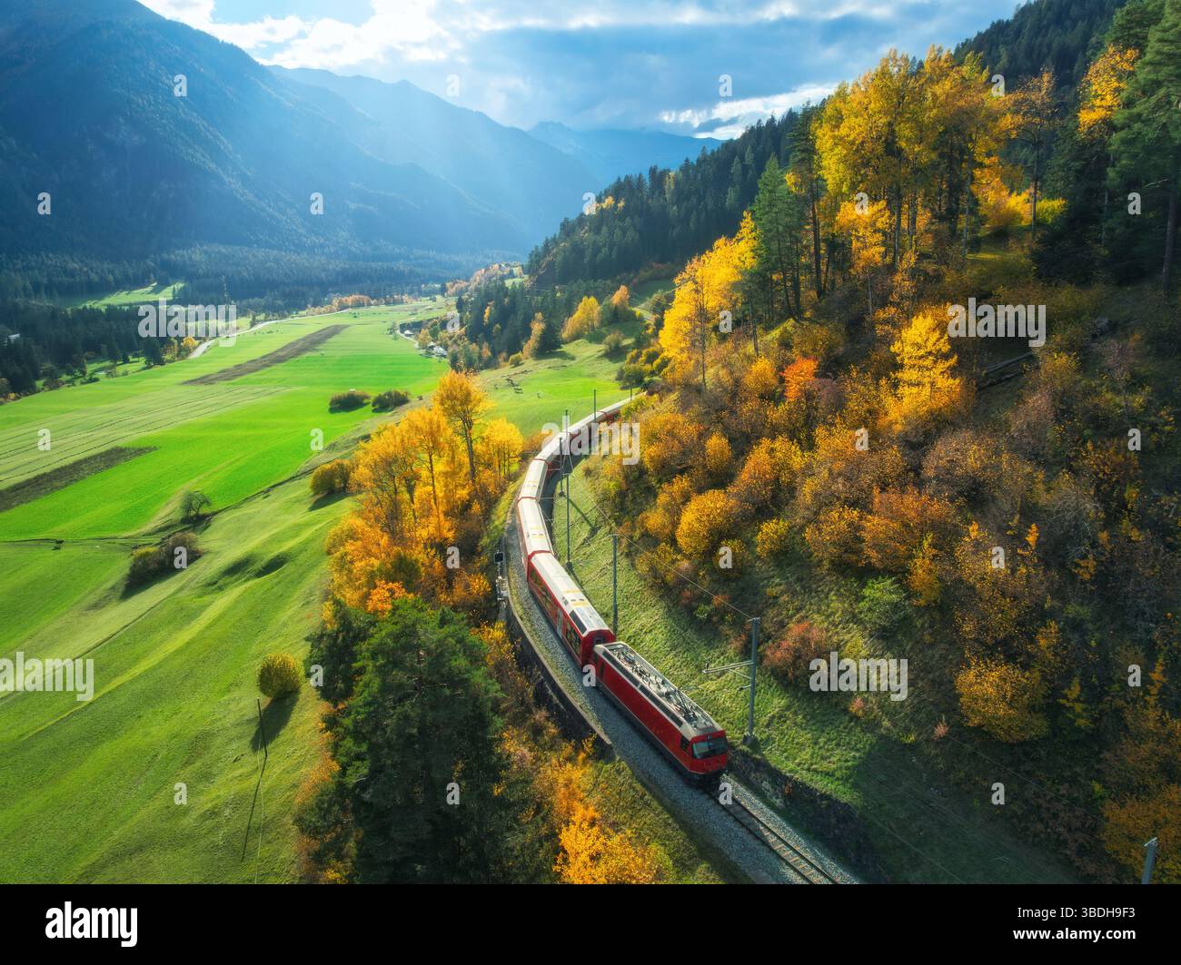 Aerial view of red train is moving in the swiss alps valley Stock Photo ...