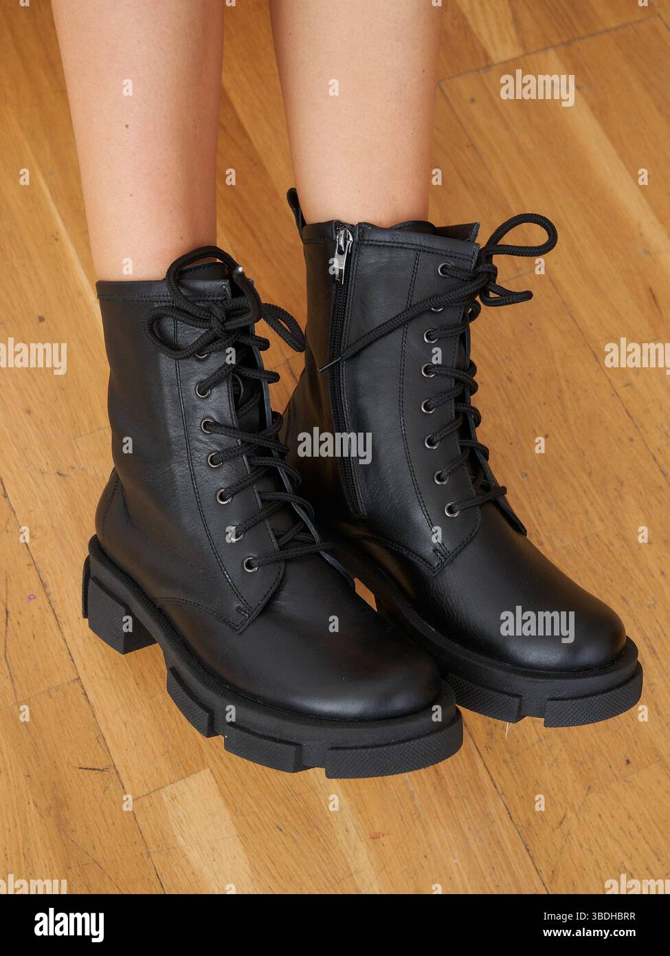 Stylish black lace-up boots complement slim female legs in a cozy ...