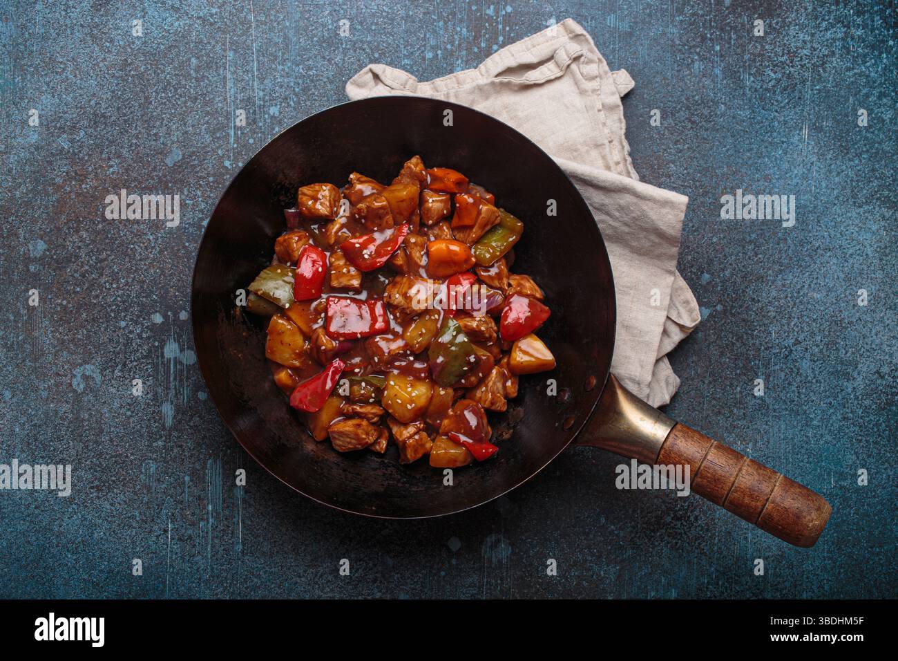 Sweet and sour pork in wok pan with peppers and pineapple top view ...
