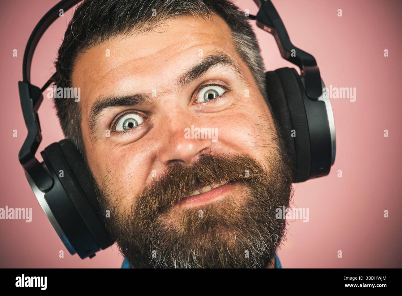 Funny bearded man listening to music in wireless headphones, closeup ...