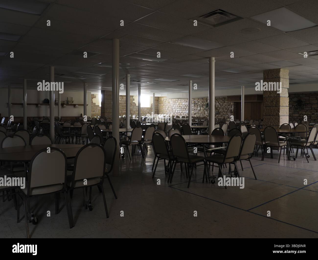 Chairs and tables in empty room dimly lit by natural light Stock Photo ...