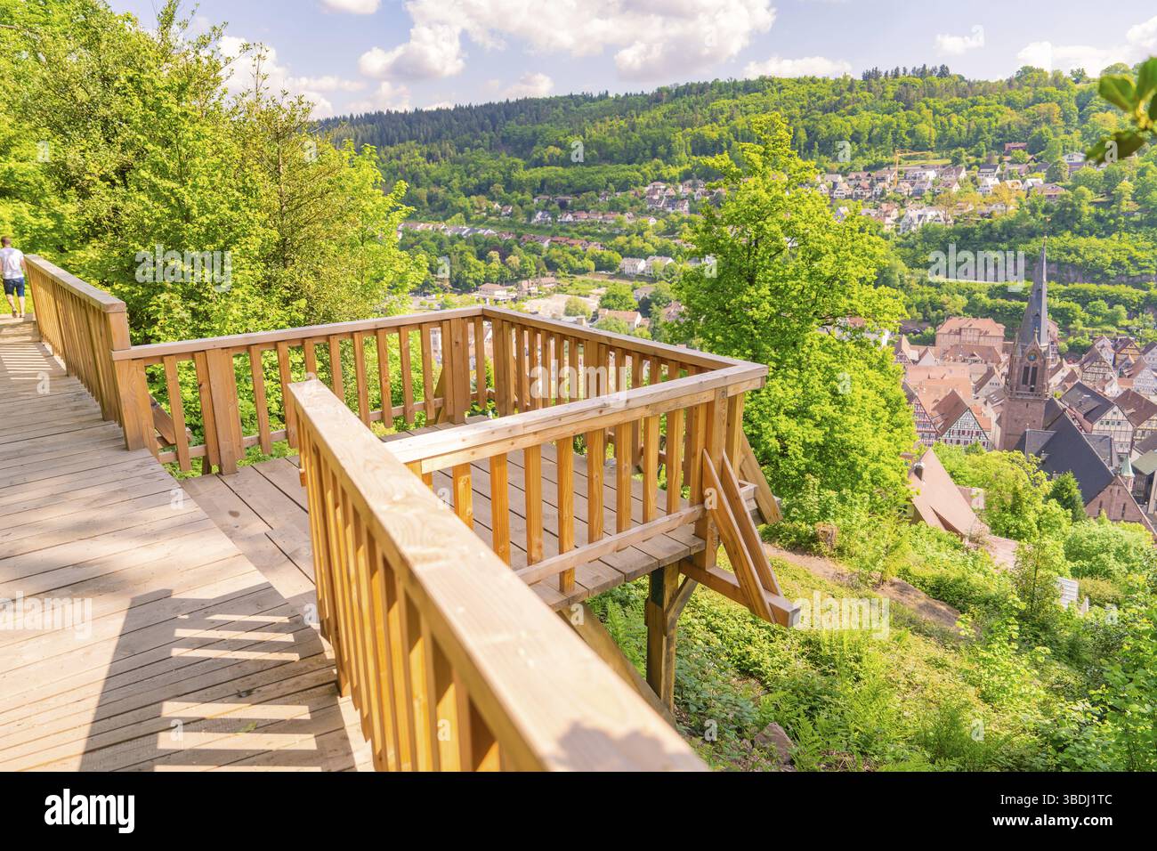 Wooden platform with a view of a cityscape surrounded by green forests ...