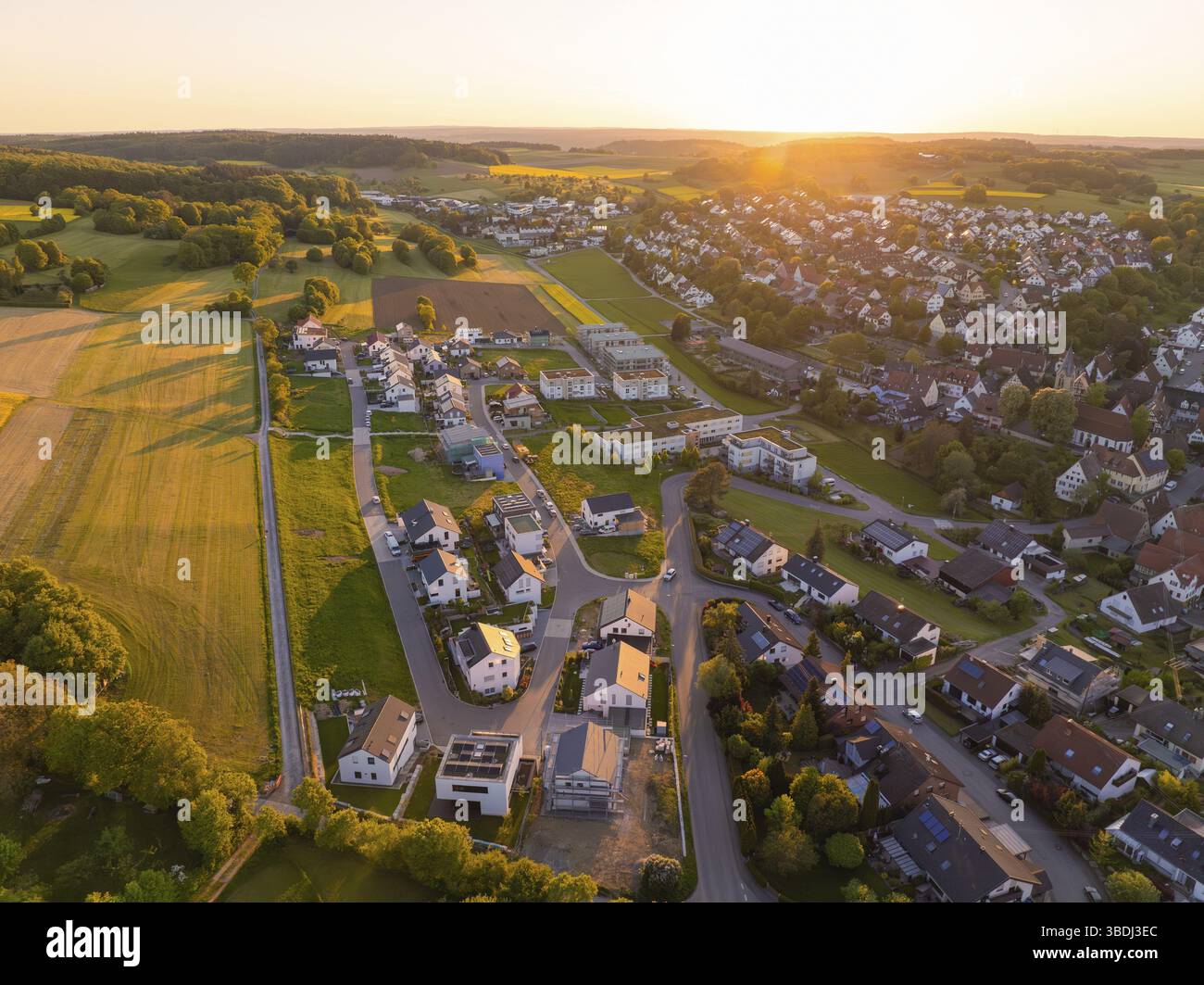 Aerial view of a rural village with houses and wide fields at sunset ...