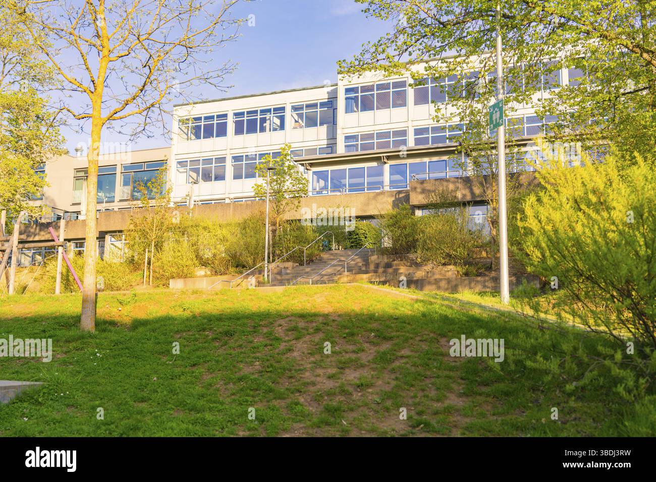 Modern building surrounded by greenery with windows and trees, under a ...