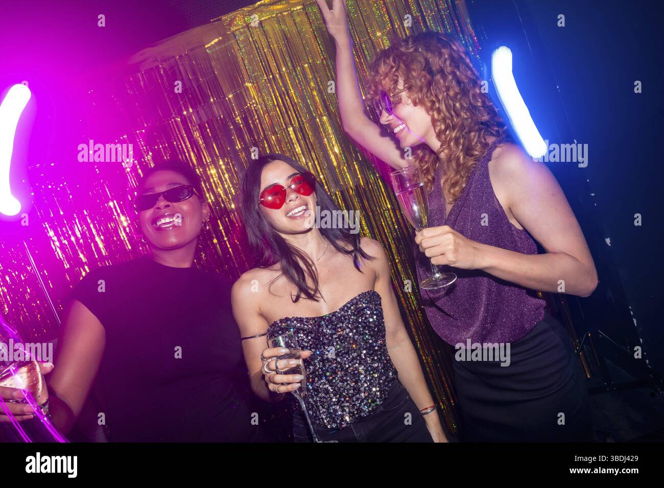 Stylish young women holding champagne glasses, dancing and enjoying ...