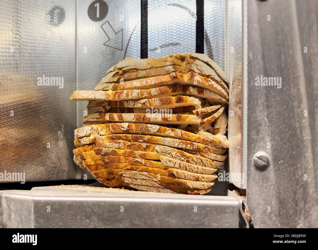 Round loaf of crusty bread partially sliced inside a commercial bread ...