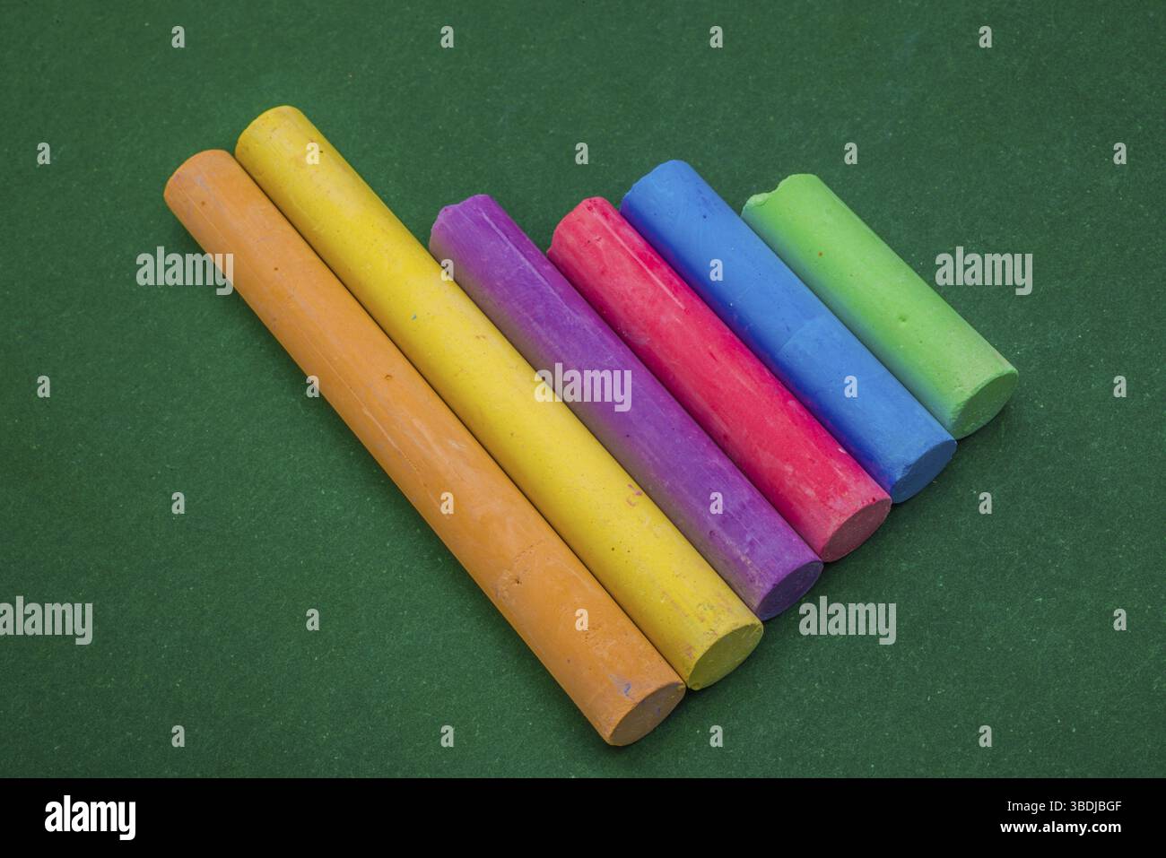 Six pieces of chalk of various sizes and different colours lie next to ...
