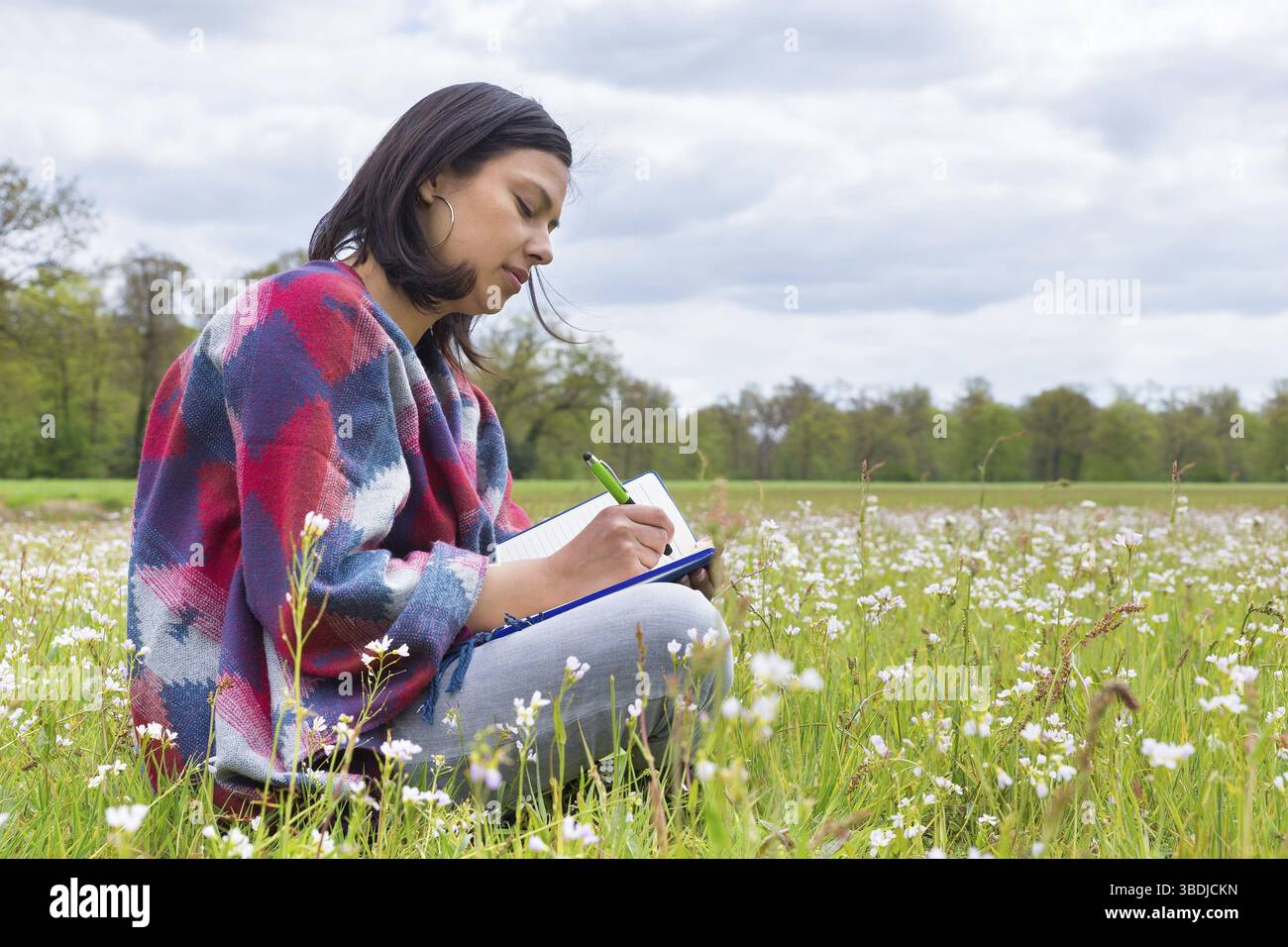 Colombian woman writes in pasture with spring flowers Stock Photo - Alamy