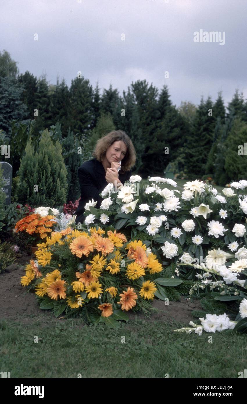 Wife, bereaved, at fresh grave, grave visit, tomb, grave site, final ...