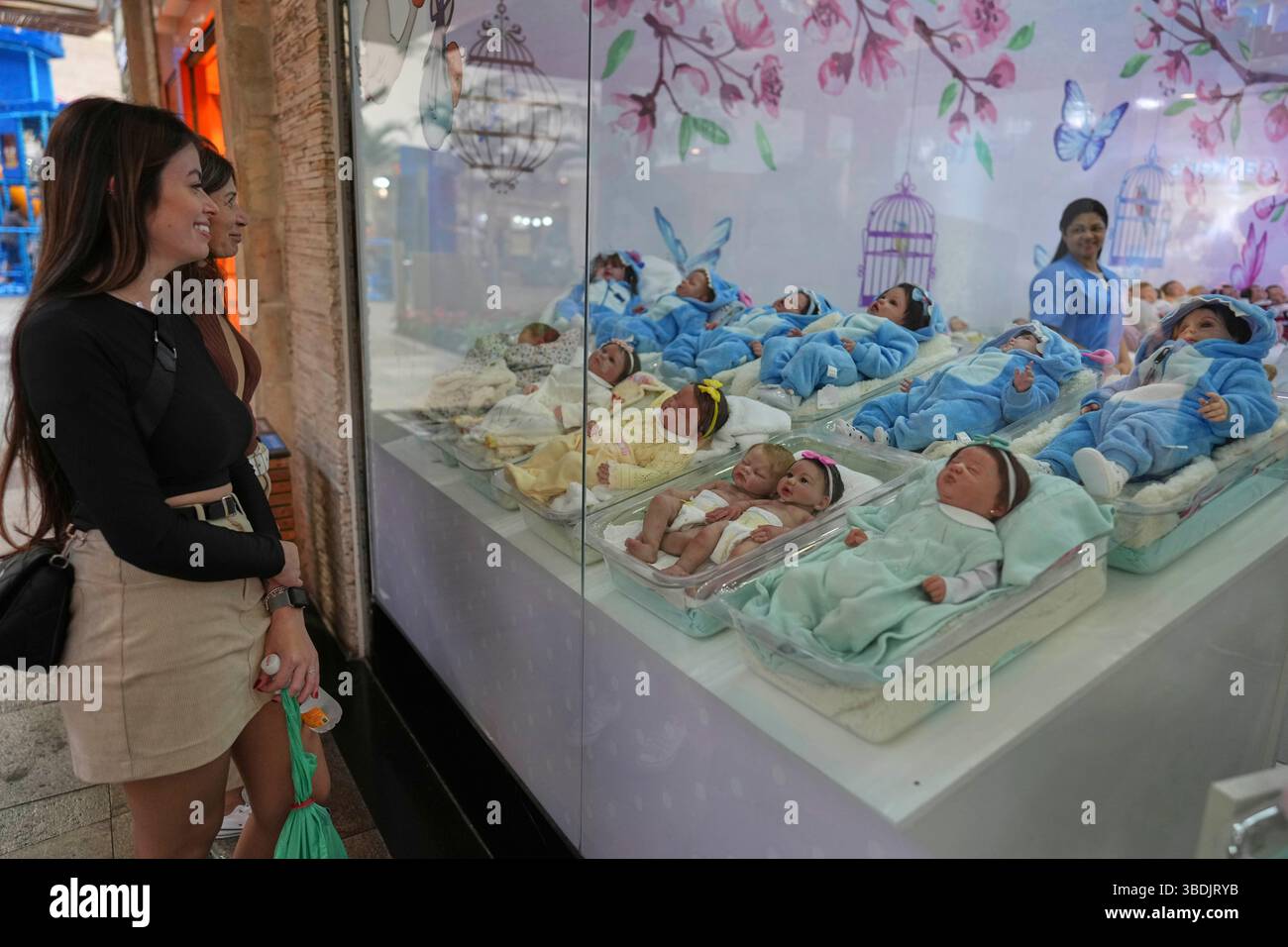 Women look at hyper-realistic reborn baby dolls displayed in a store ...