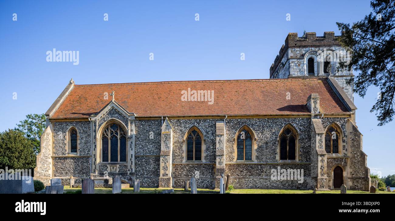 Side elevation of a long, historic flint church with a red tiled roof ...