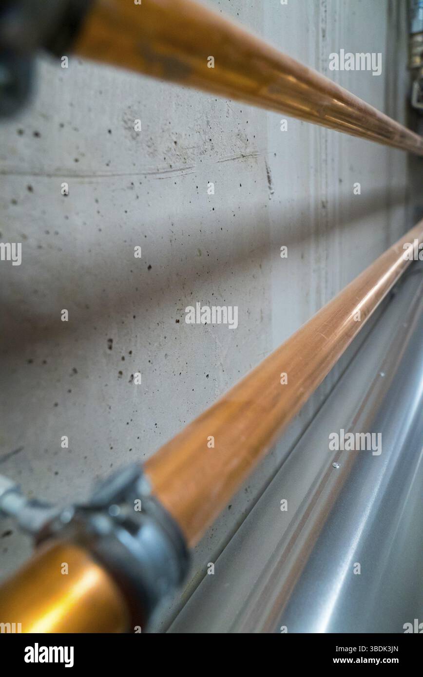 horizontal view of long new shiny copper pipes leading along a concrete ...