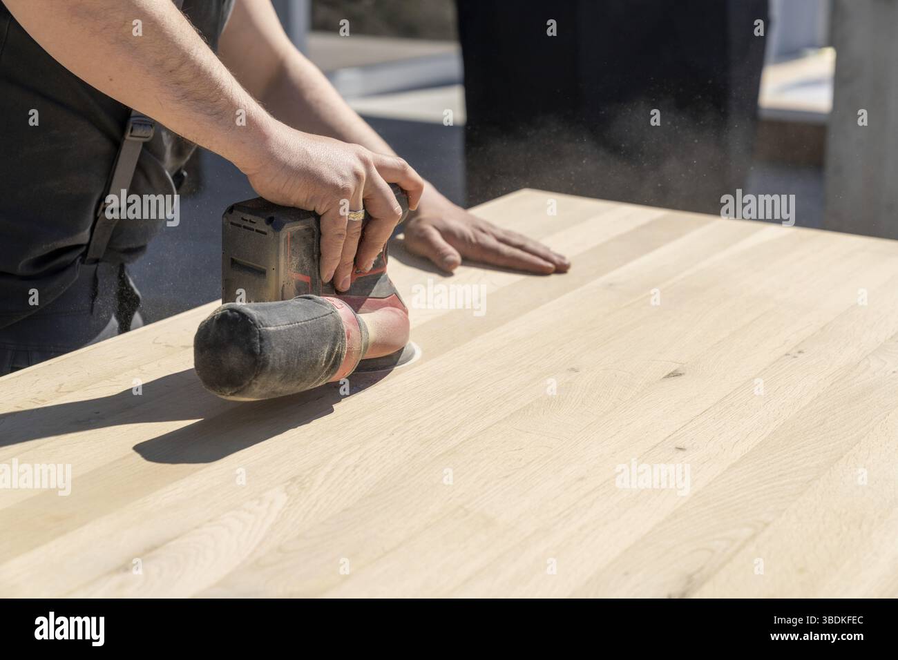 A construction worker using a cordless power sander to sand a massive ...