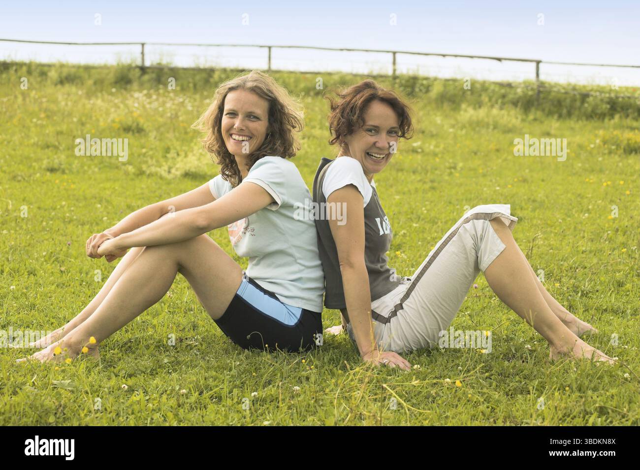 Women sit back to back Stock Photo - Alamy