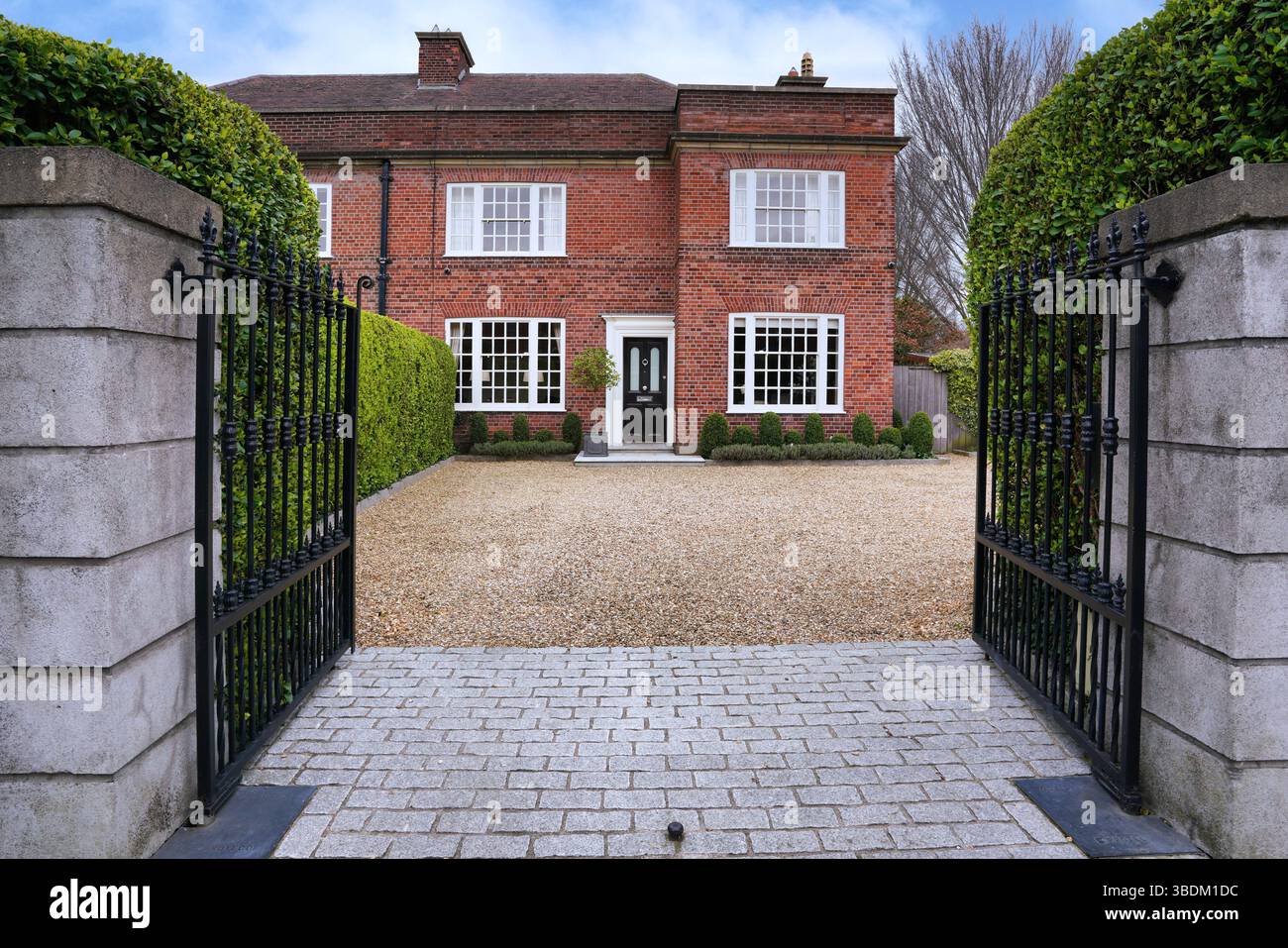 Brick home with open gate leading to gravelled front yard Stock Photo ...