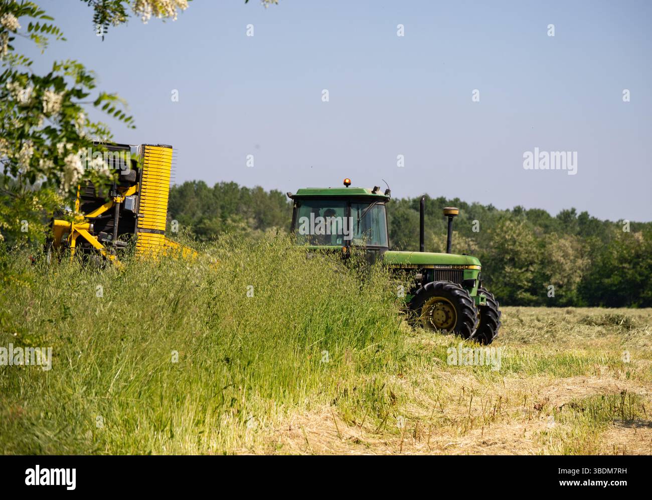 Farm equipment, a John Deere tractor, operates in a lush field ...