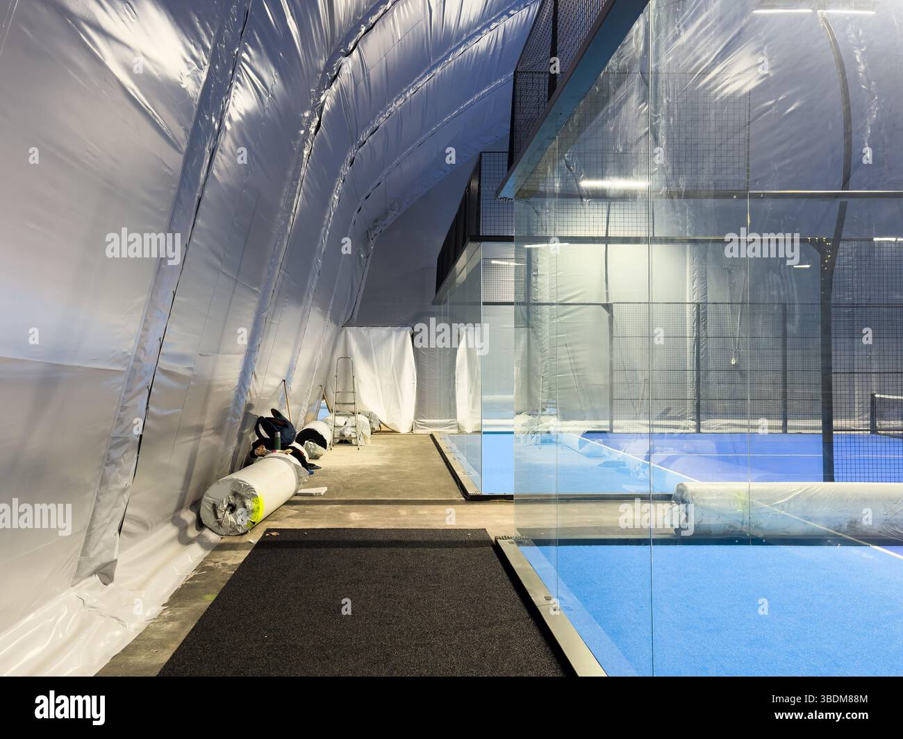 Under a vast modern structure, newly installed padel courts. Centered ...