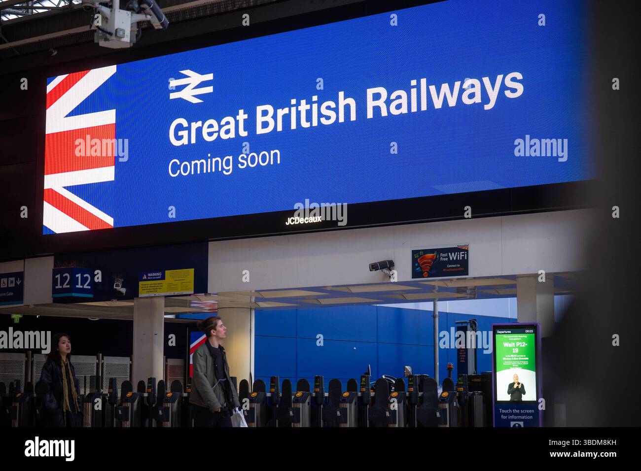 People walk past signage at Waterloo train station in central London as ...