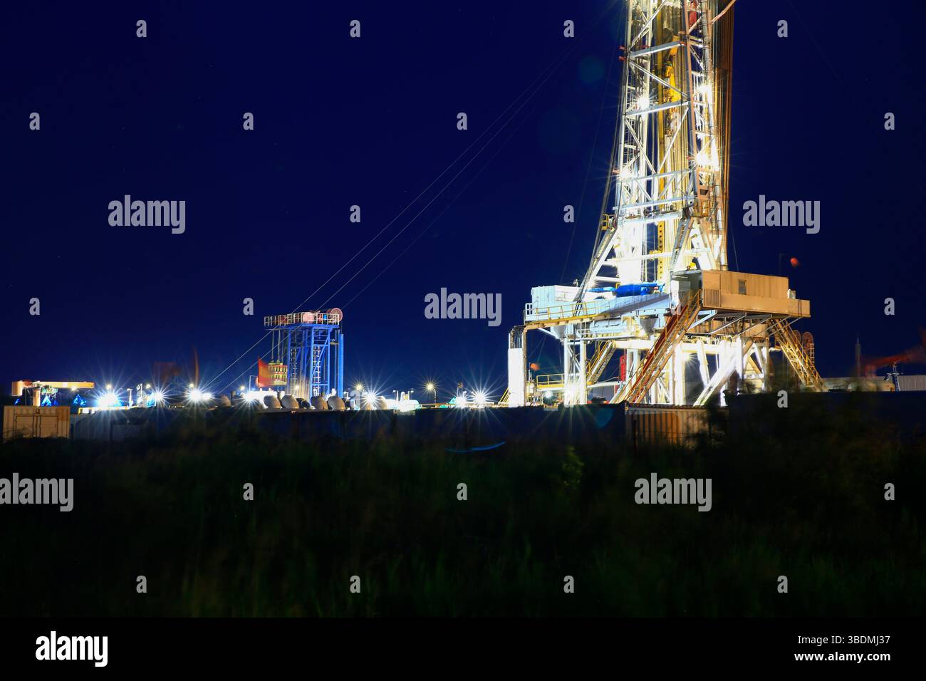 Oil drilling rig，Oil rig at the background of refinery by night. Oil ...