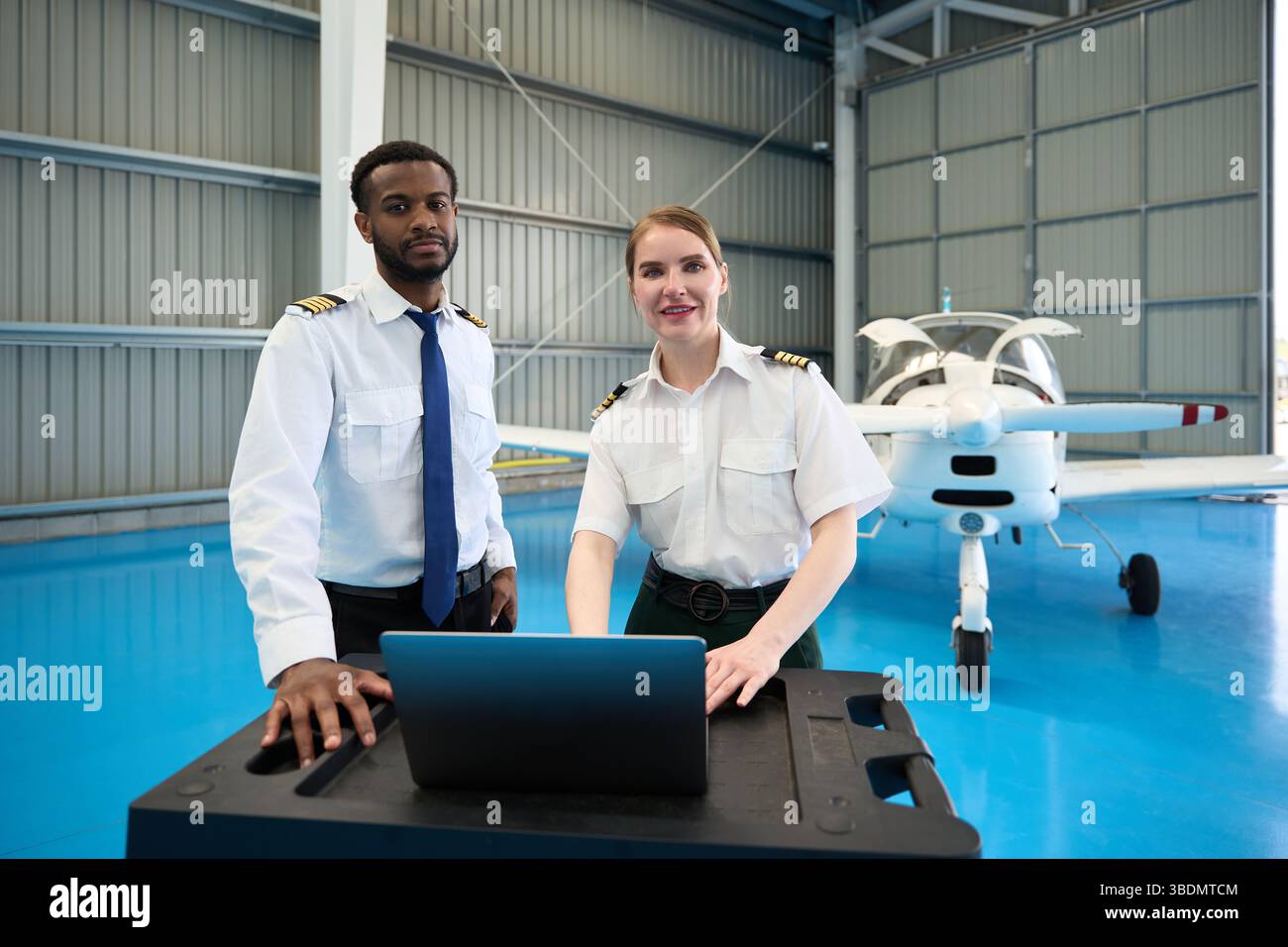 Aircraft maintenance training: pilots using laptop in hangar with small airplane Stock Photo - Alamy