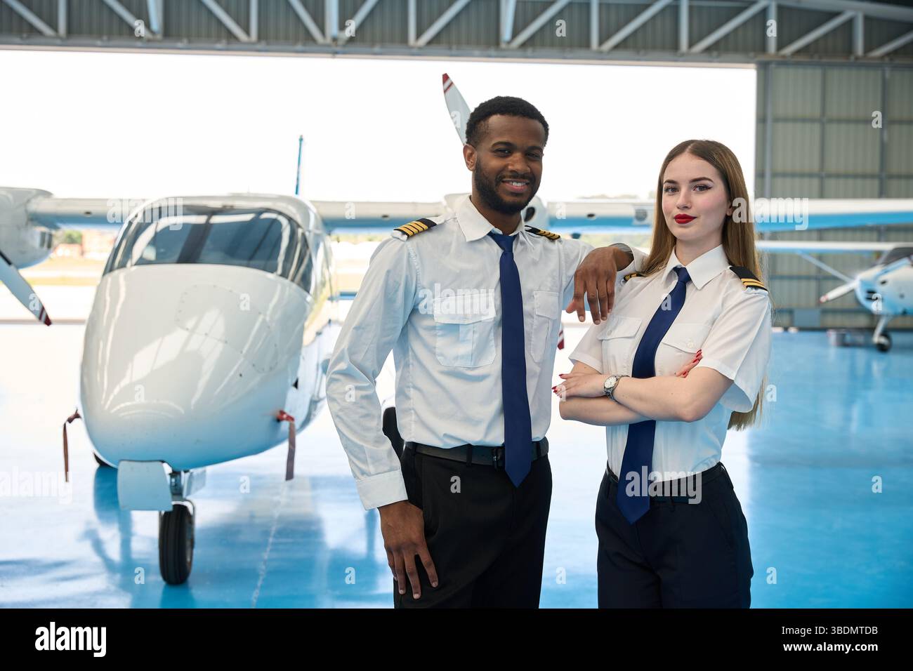 Student pilots posing in front of aircraft in hangar Stock Photo - Alamy