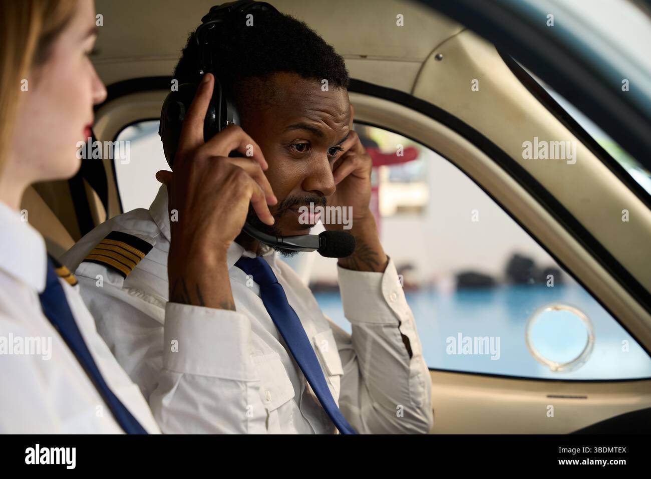 Student pilot adjusting headset in cockpit with instructor beside him ...