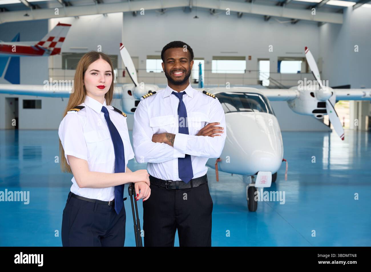 Smiling pilot students posing in aircraft hangar Stock Photo - Alamy