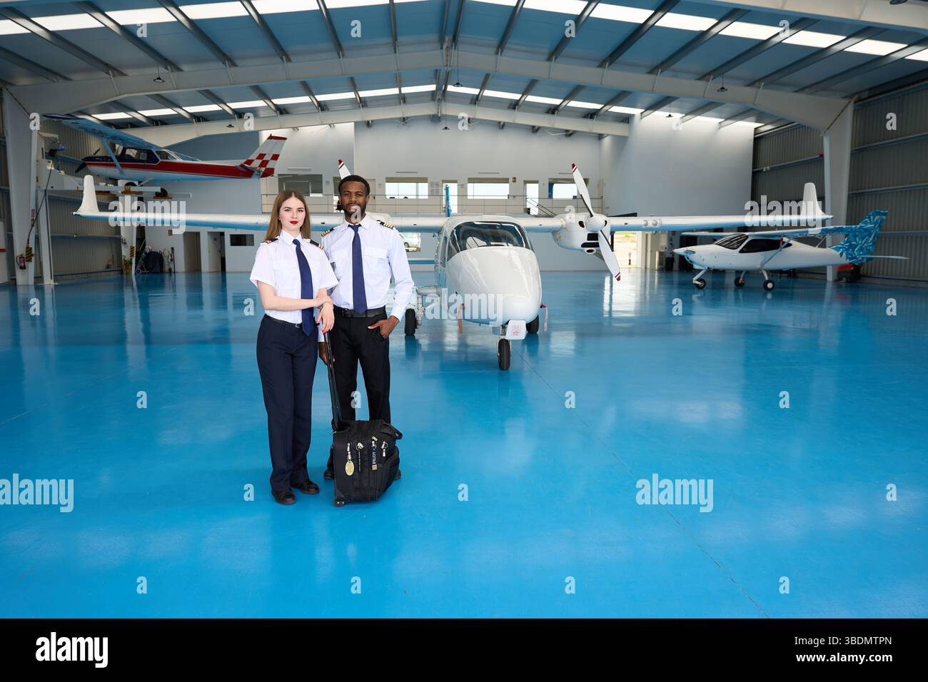 Student pilots posing in aircraft hangar with light aircraft Stock ...