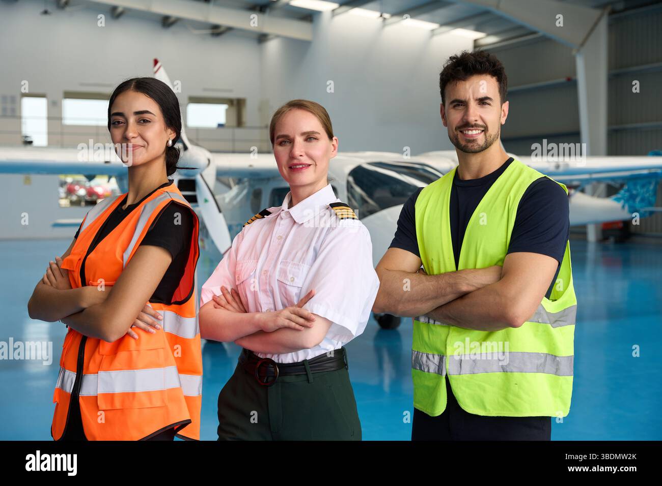 Pilot and aircraft mechanics smiling in hangar with light aircraft ...