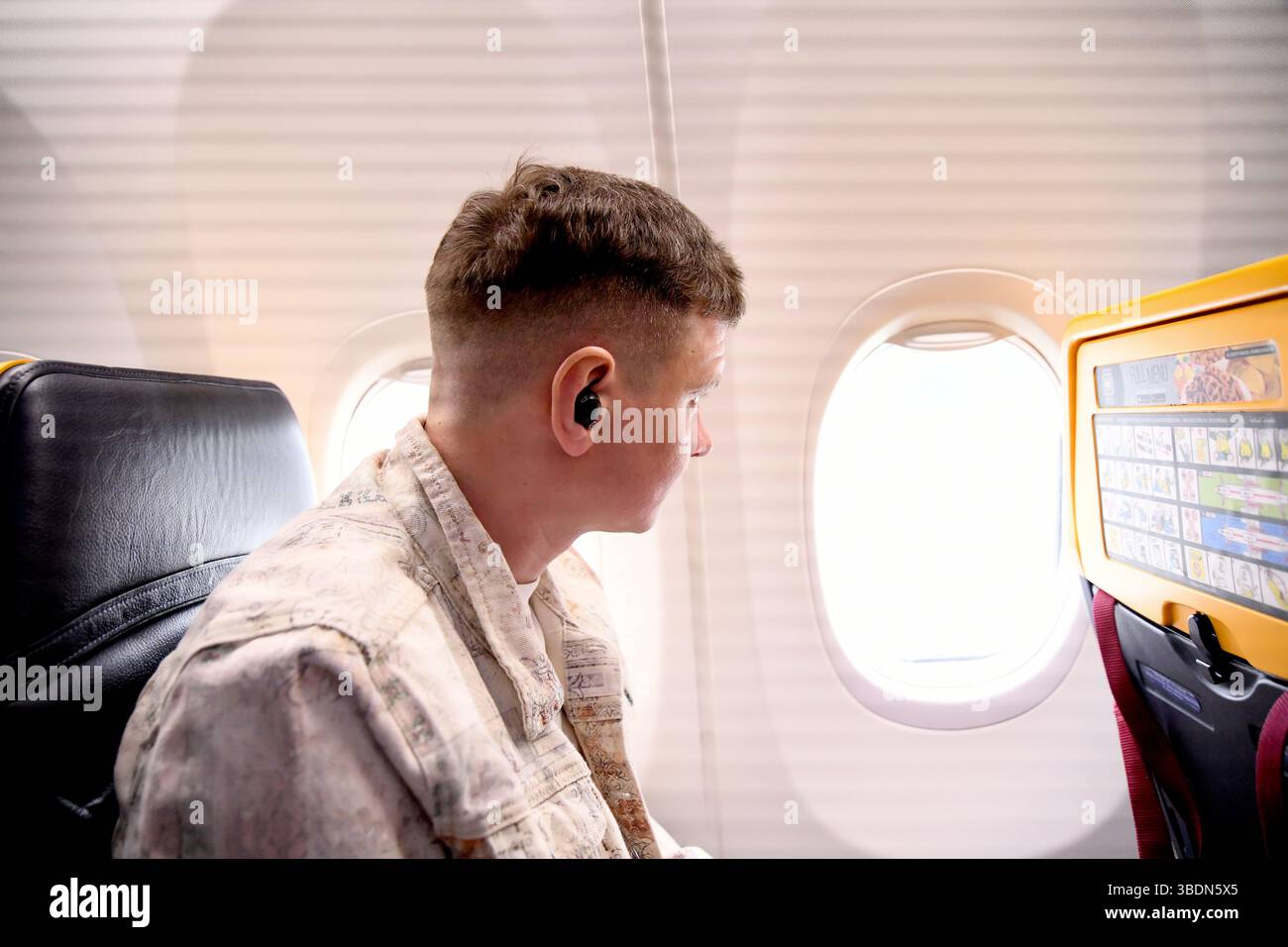 Passenger at the airplane window wearing headphones, looking out Stock ...