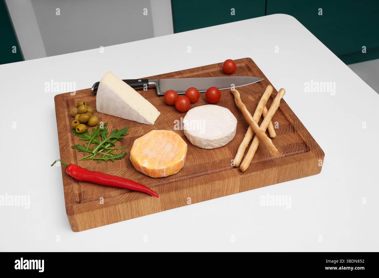 Cheese board on a white table. Different types of cheese, tomatoes ...