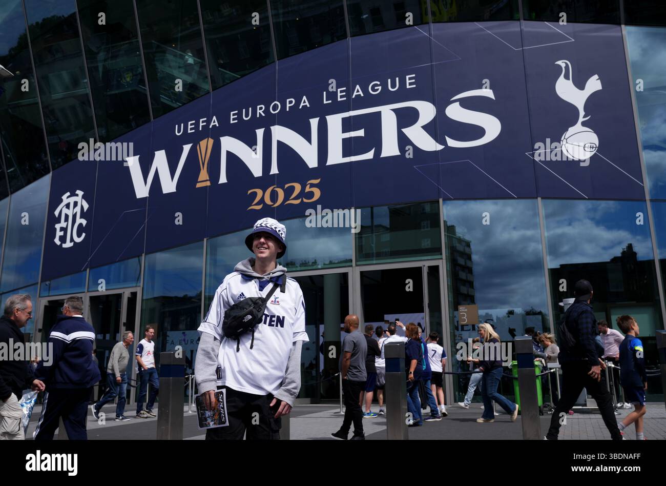 A Tottenham Hotspur fan poses for a photo under a sign displaying ...
