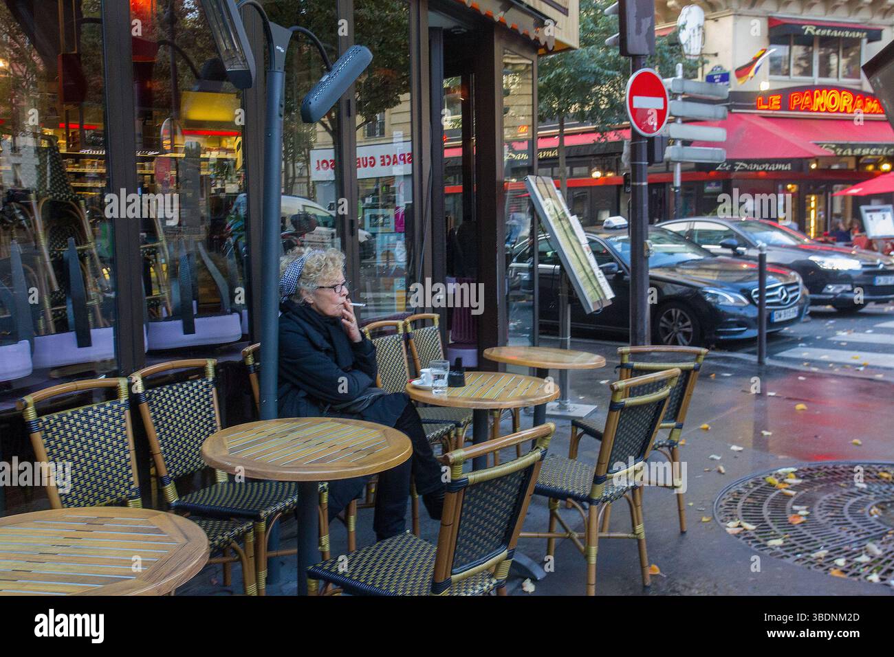 10-25-2025 PARIS Elderly woman smoking on a chair in a French cafe in ...