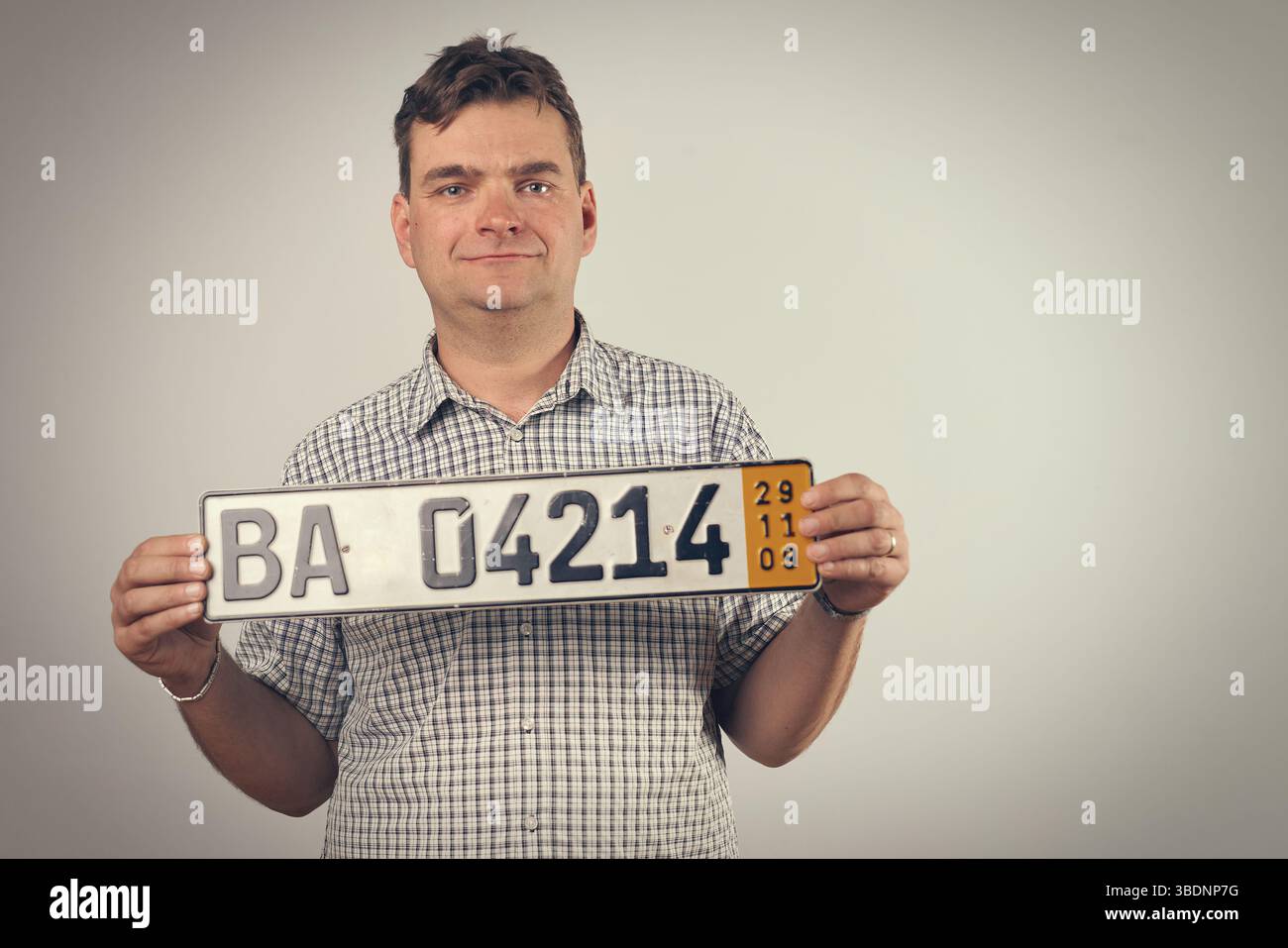 Man in studio on gray background posing with registration plate Stock ...