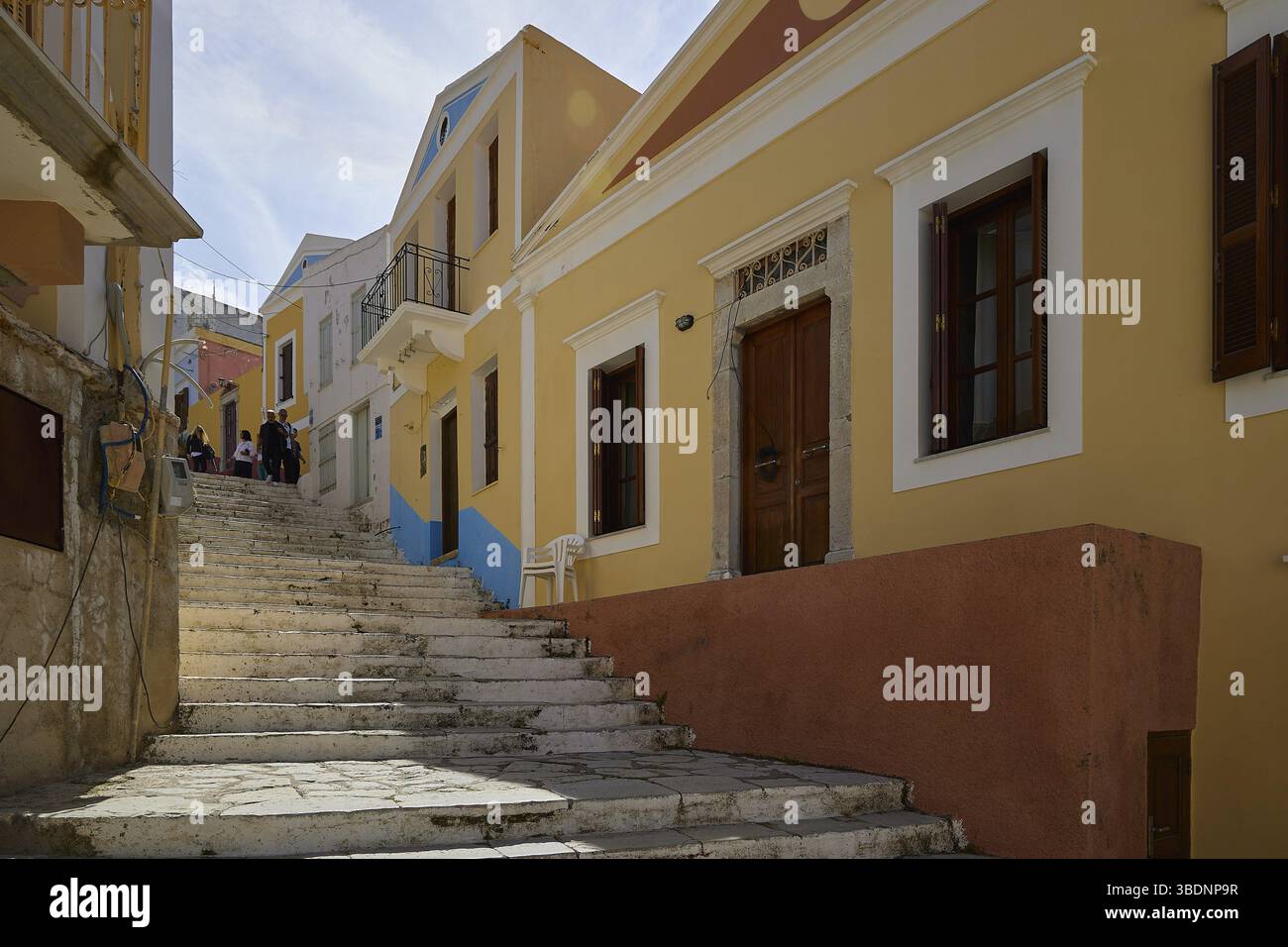Narrow stairway flanked by yellow houses, in the sunshine, Symi Town ...