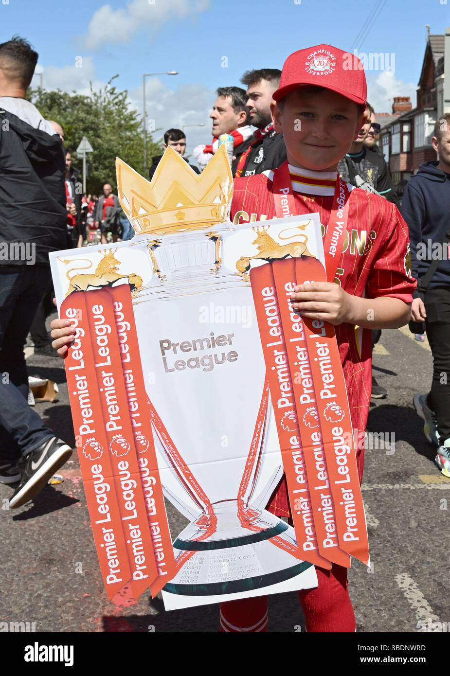 A young Liverpool fan holding a cardoard Premier League trophy before ...