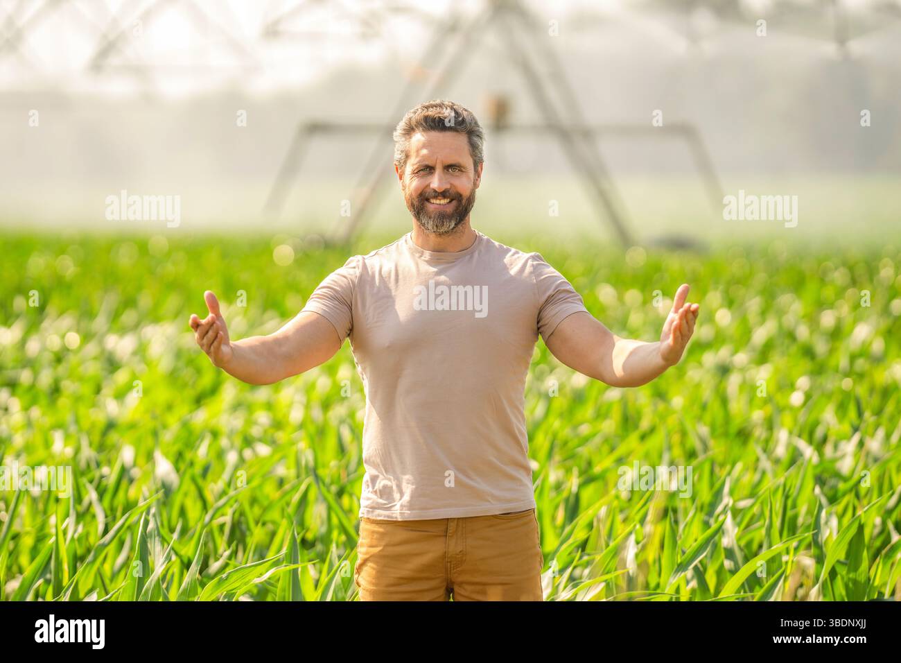 Farmer man presenting field. Water sprinkler irrigating crop. Drip ...