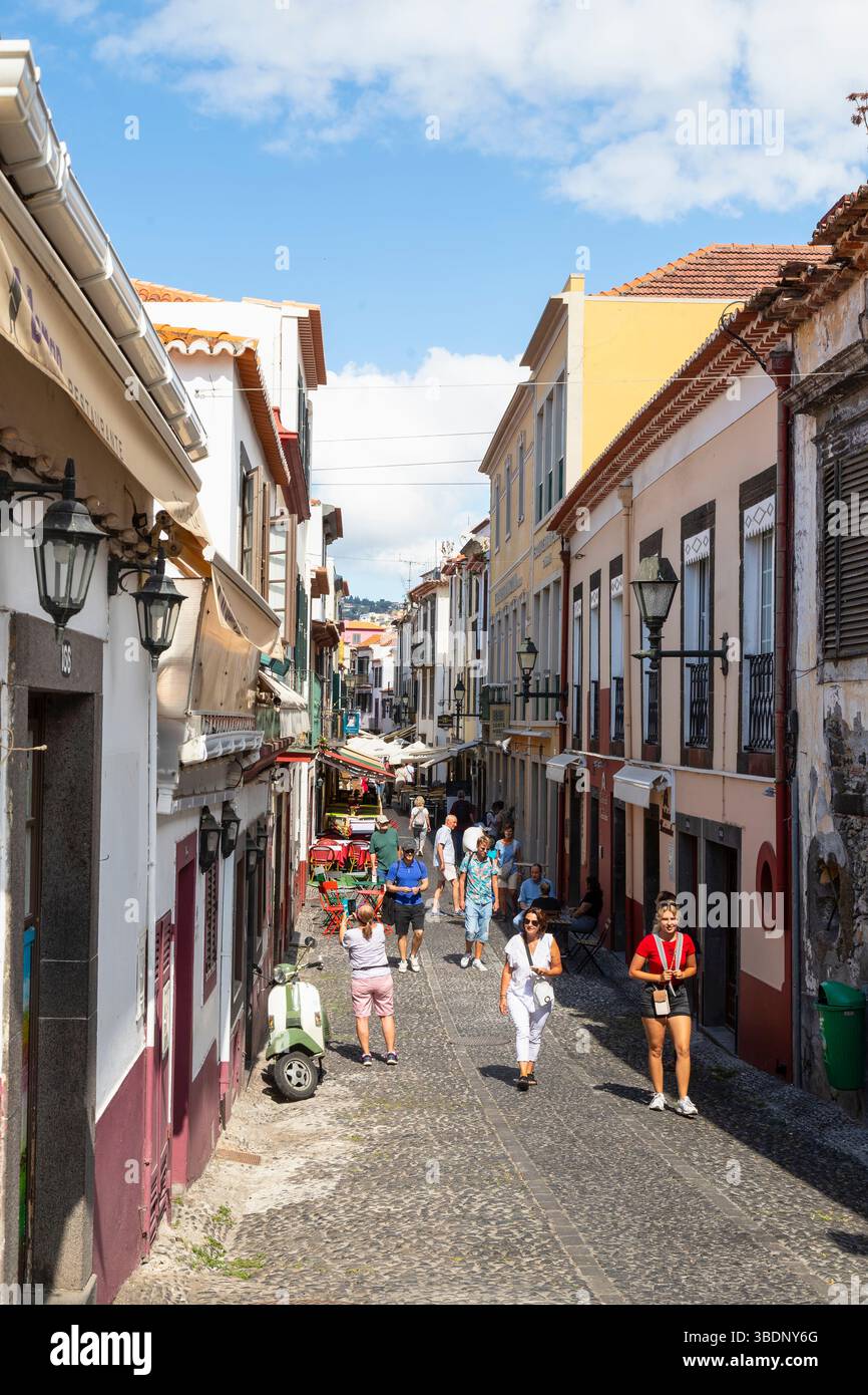 People stroll through the cozy Santa Maria street with shops, bars and ...