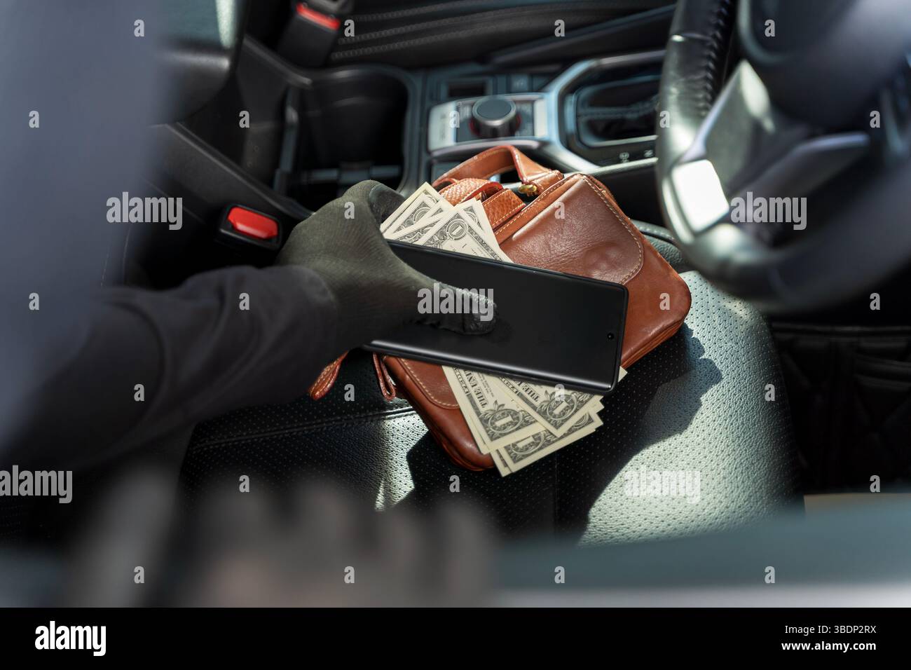 A thief’s gloved hand stealing smartphone and dollar bills from a ...