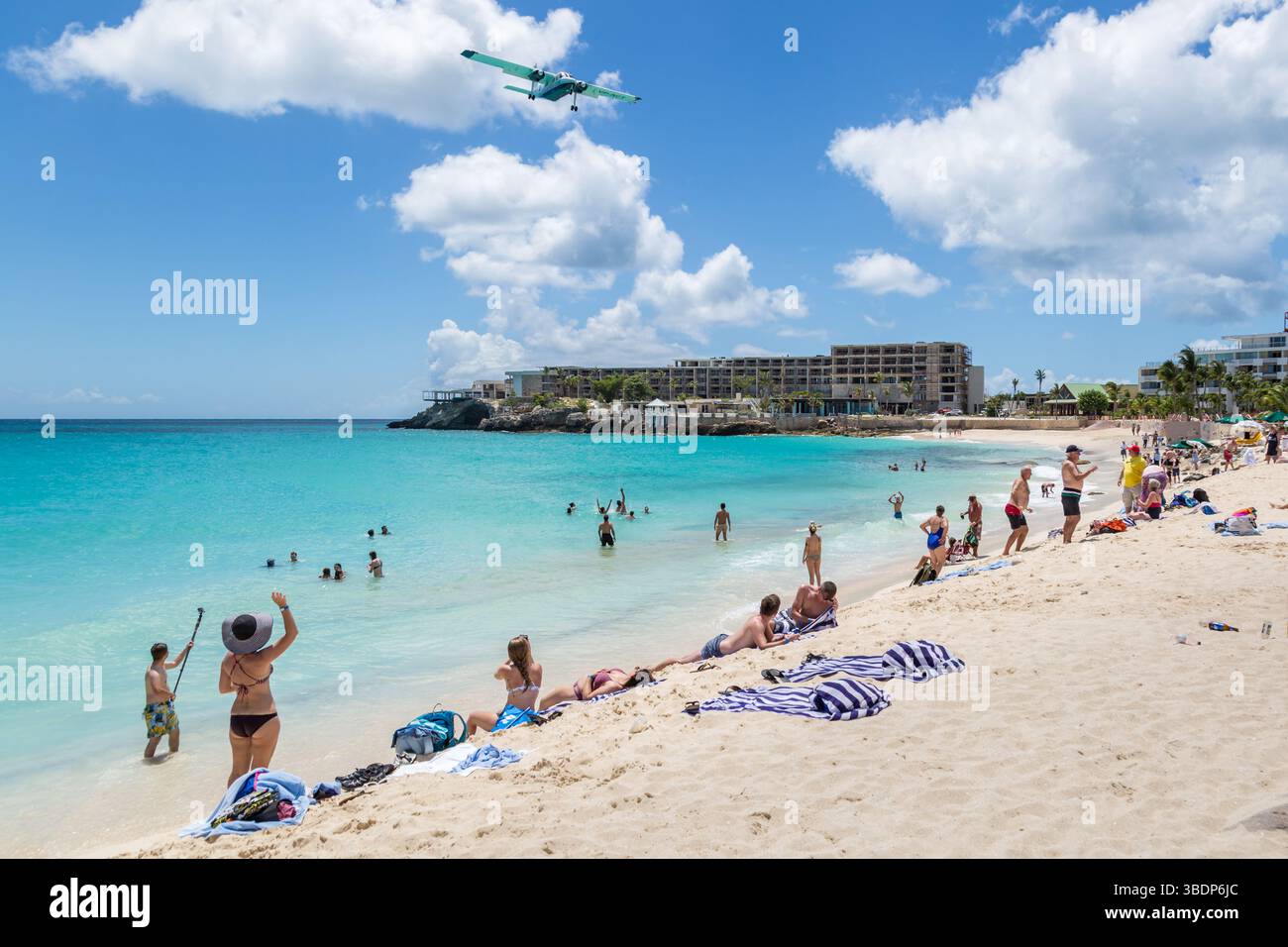 Swimmers wave to airplane flying low over Maho Beach on final approach ...