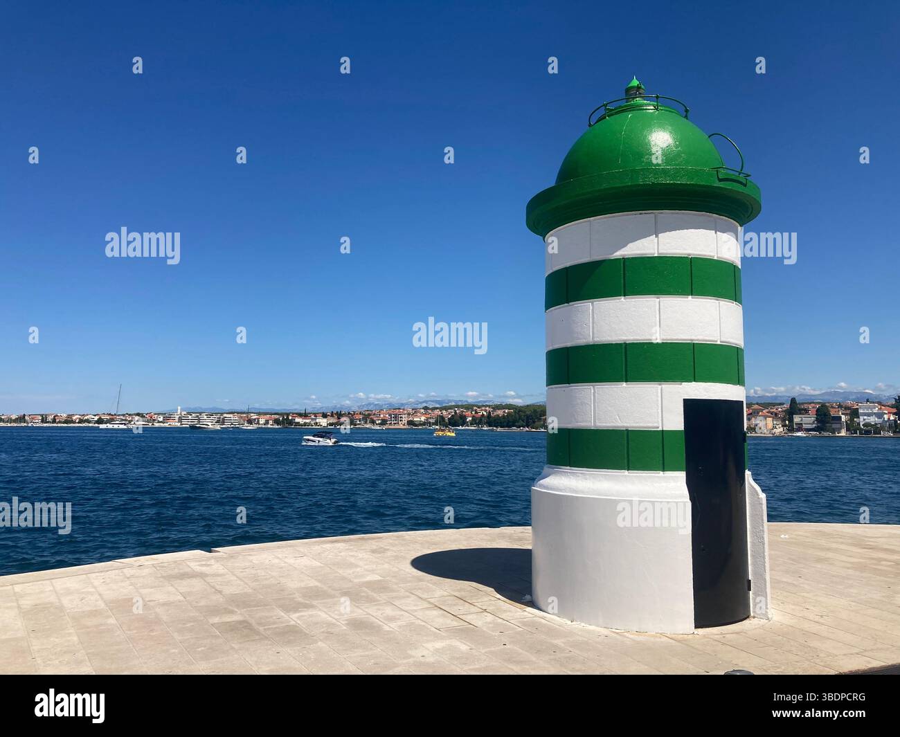Small green bollard lighthouse on Zadar dock, used for maritime ...