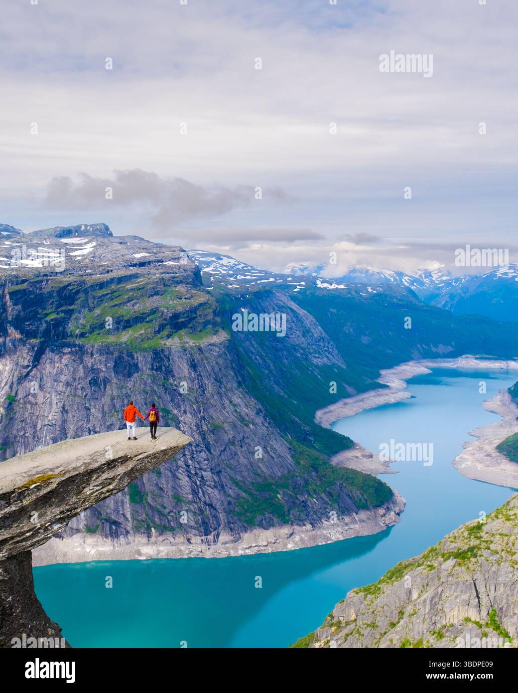 Hikers stand on the edge of Trolltunga, Norway, marveling at the ...